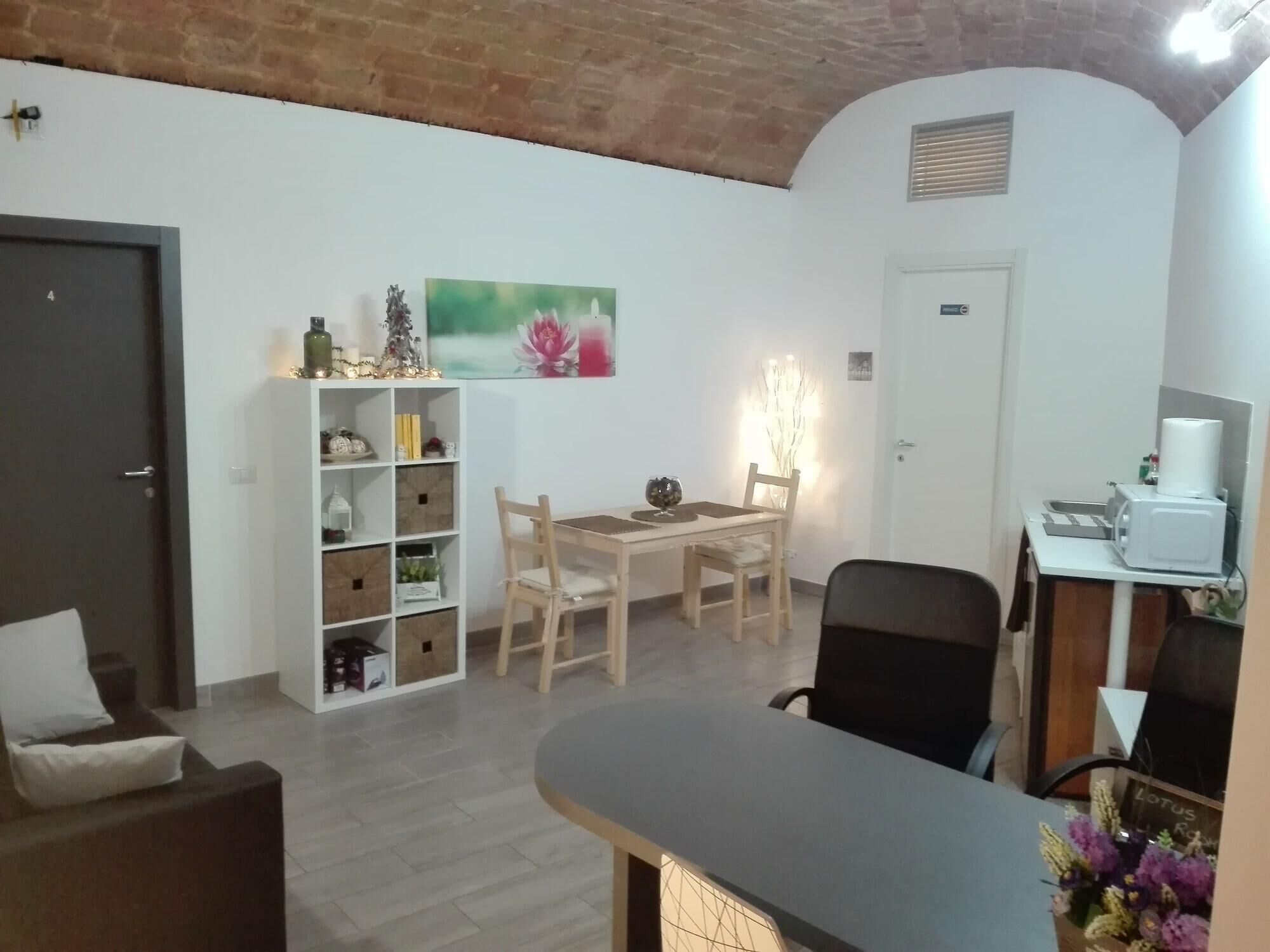 Um quarto com uma mesa de jantar, cadeiras, um armário branco com prateleiras, um quadro e uma porta.