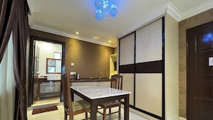 Uma área de refeições com mesa e cadeiras, uma cozinha ao fundo e uma luminária decorativa no teto.