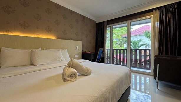 Quarto de hotel com cama grande, escrivaninha e vista para o exterior.