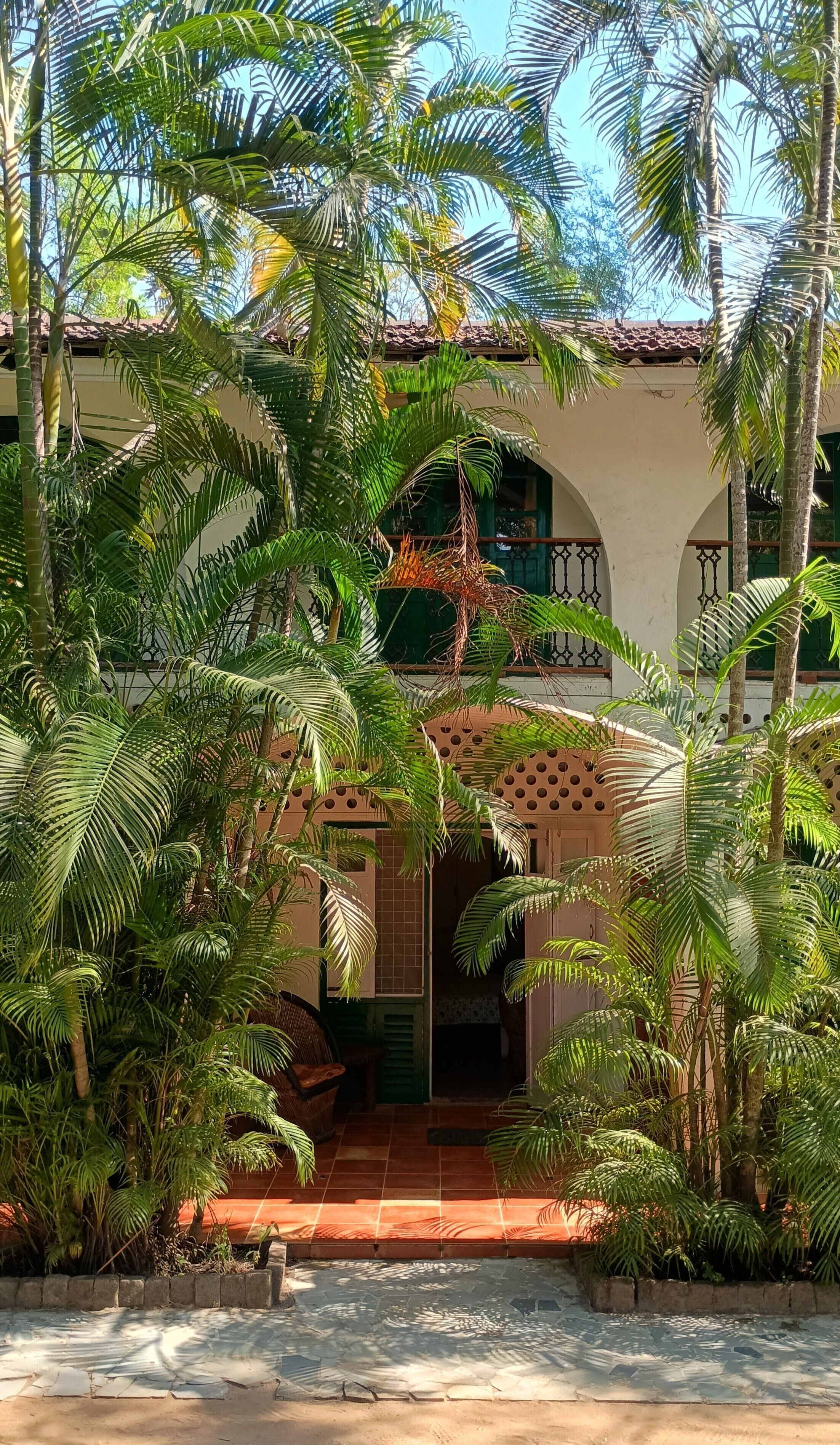 Um edifício com telhado em telhas, entrada em arco e varanda com grade.
