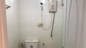 Casa de banho pequena e compacta, com sanita, cabine de duche e caixa elétrica na parede.