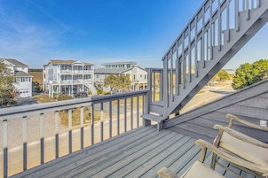 Um deck de madeira com guarda-corpo, com vista para uma área residencial com casas.