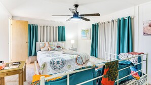Quarto com beliche, ventilador de teto e cortinas verde-água.