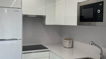 Um frigorífico/congelador grande, um micro-ondas, uma placa de cozinha