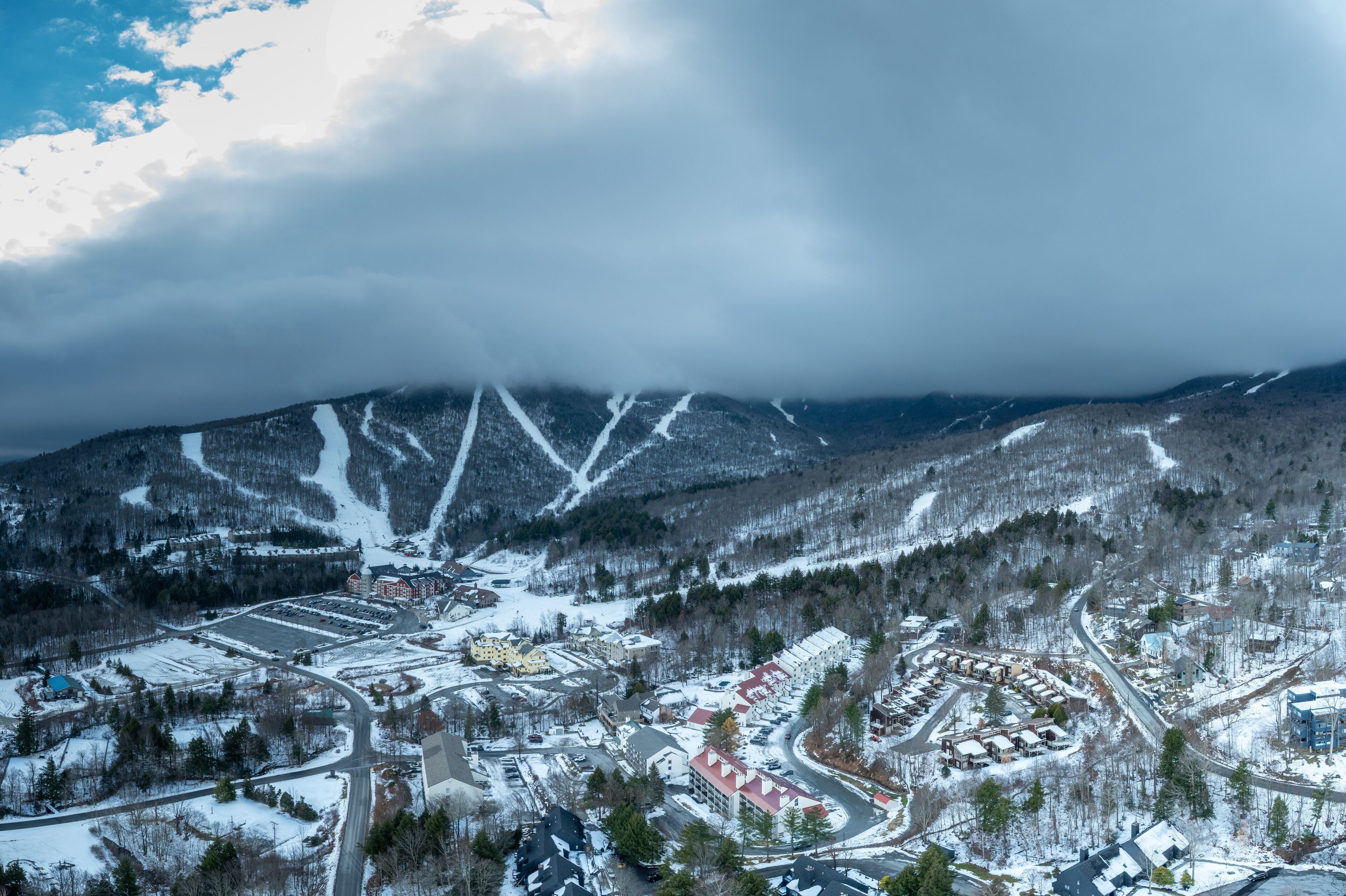Uma área montanhosa coberta de neve com uma estação de esqui, incluindo pistas de esqui e edifícios.