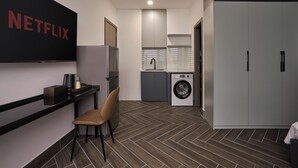 Quarto de hotel moderno com televisão de tela plana, uma cadeira, máquina de lavar e armário.