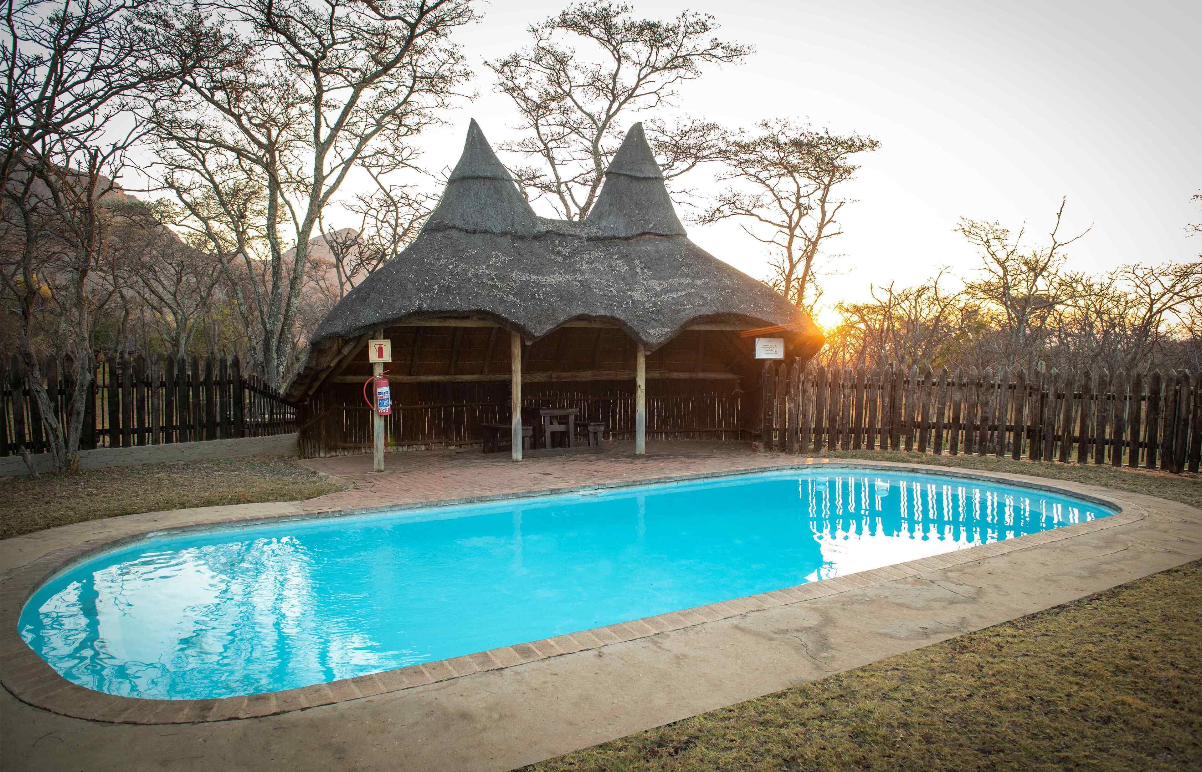 Piscina com uma estrutura de telhado de palha ao fundo.