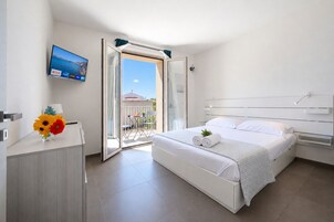 Quarto de hotel moderno com cama, escrivaninha, televisão e varanda com vista.