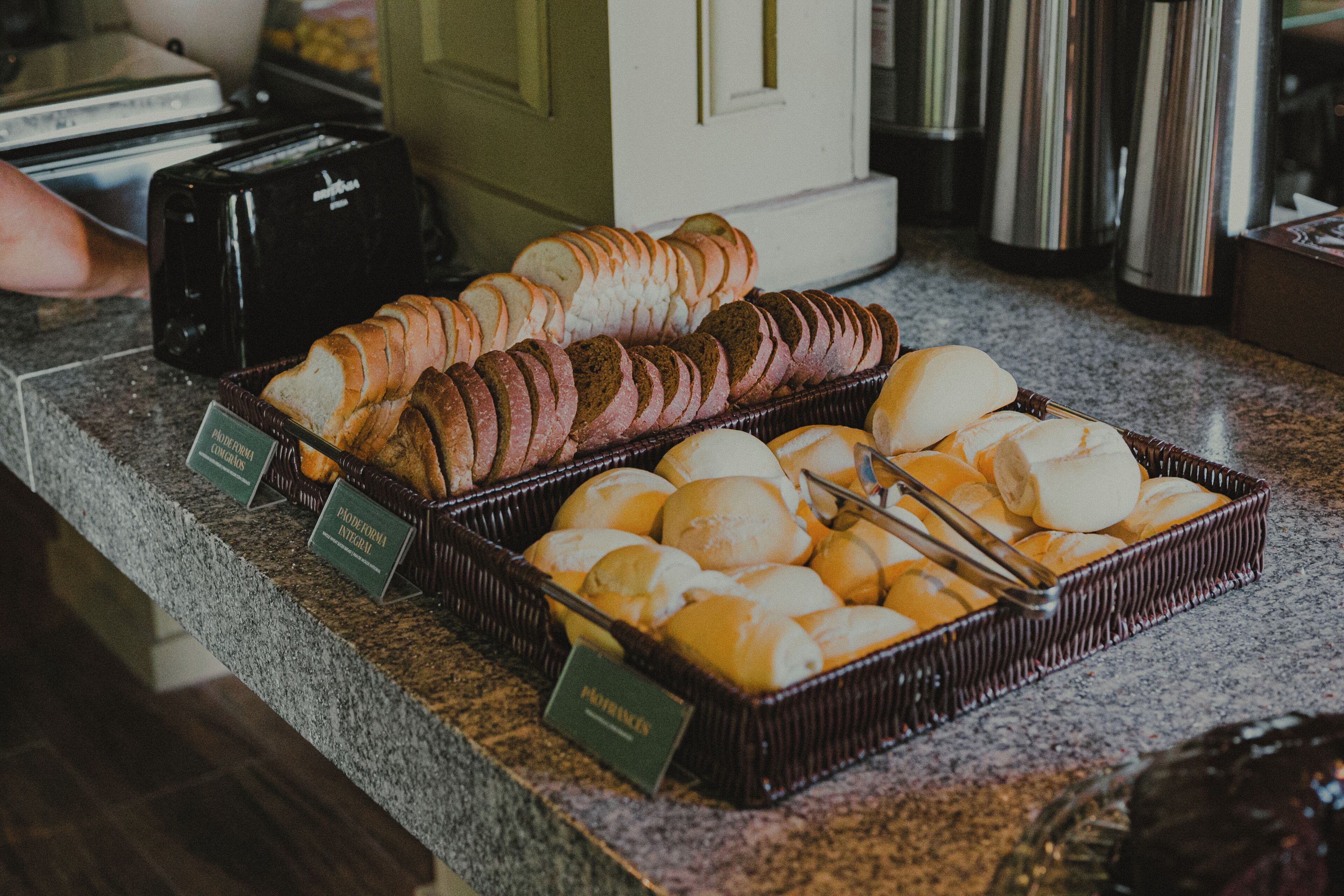 Buffet com diversos pães e doces.