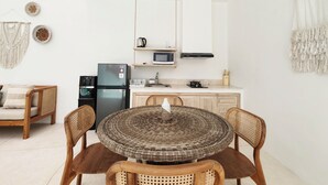 Uma cozinha moderna com geladeira, micro-ondas e fogão pretos, uma mesa de jantar redonda de madeira com quatro cadeiras e um ventilador de teto.