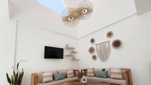 Uma sala de estar moderna com um amplo sofá em formato de L, uma mesa de centro de madeira, uma planta em vaso e detalhes na parede.