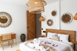 Quarto com cama de madeira, uma escrivaninha e abajur de vime.