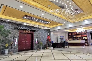 Um saguão de hotel com balcão de recepção, uma porta vermelha grande e teto decorativo.