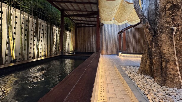 Uma fonte interior tranquila com paredes de bambu e um caminho de madeira.