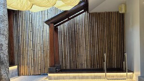 Uma área de spa moderna com parede de madeira, piso aquecido e um banco de pedra.