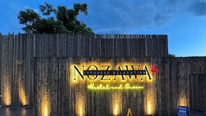 Pared de madeira com sinalização iluminada para Nozawa Japanese Relaxation, incluindo um letreiro de neon e um letreiro de boas-vindas.