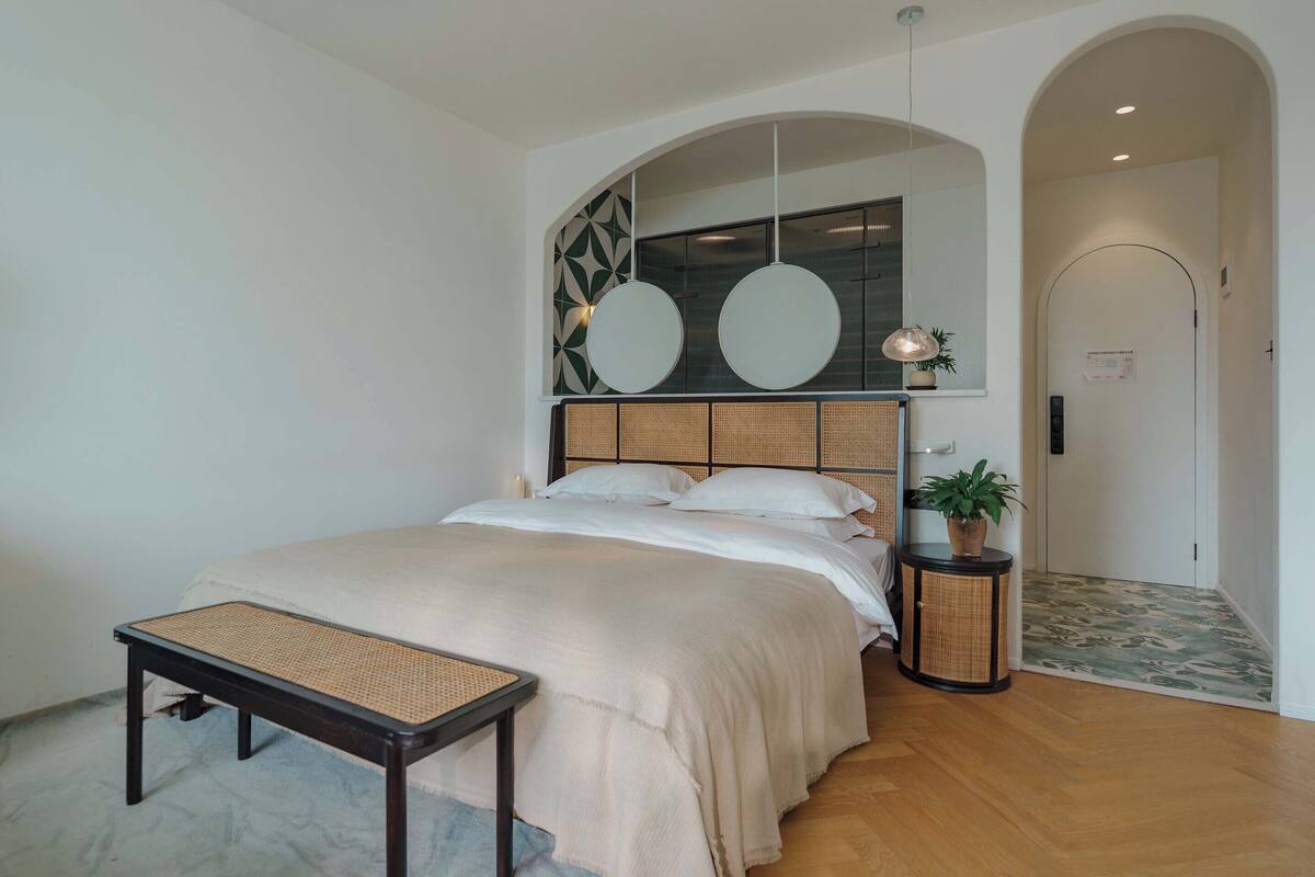 Quarto bem arrumado com cama, mesa de cabeceira e uma pequena planta em vaso.