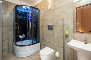Uma casa de banho moderna com cabine de duche em vidro, sanita branca e lavatório.