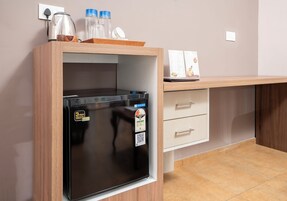 Uma cozinha compacta com geladeira preta, cafeteira e micro-ondas na bancada.
