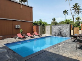 Piscina com espreguiçadeiras e parede de pedra.