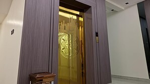 Interior moderno com porta de madeira, uma pequena mesa e piso coberto por carpete.