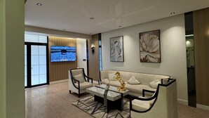 Uma sala de estar moderna com um sofá, duas poltronas, uma mesa de centro e uma televisão.
