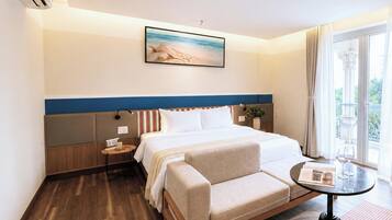 Quarto de hotel com uma cama, mesa de cabeceira, cadeira, pequena mesa com copos e uma janela com cortinas.