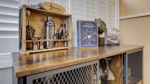 Balcão de madeira com um livro de coquetelaria e agitadores.