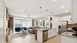 Uma cozinha moderna com ilha central, eletrodomésticos de aço inoxidável e iluminação pendente.