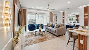 Uma sala de estar moderna com sofá, mesa de centro e área de jantar. Há uma janela grande que oferece luz natural e vista para o exterior.