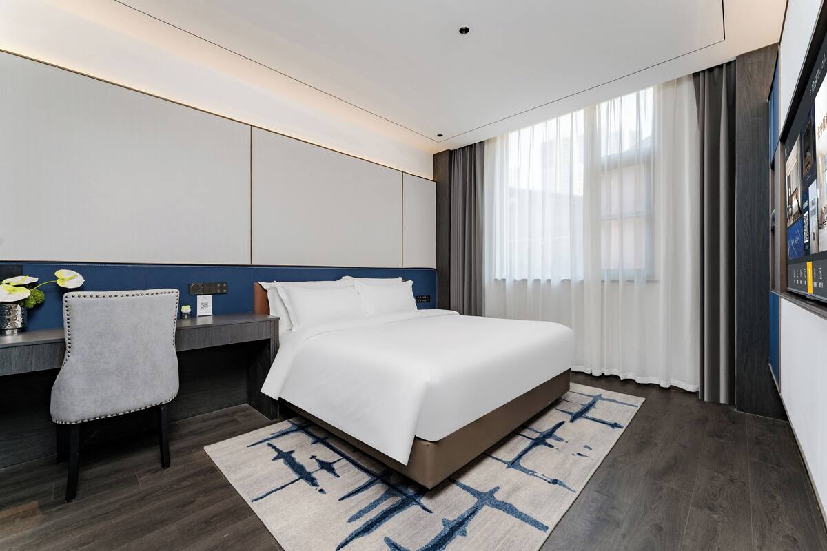 Quarto de hotel moderno com uma cama grande, uma escrivaninha e uma cadeira.