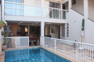 Um edifício de dois andares com piscina, área de estar externa e varanda.