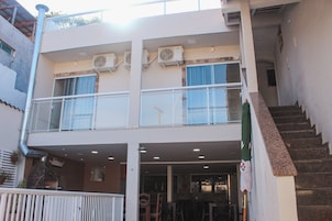 Um edifício de dois andares com varanda, aparelhos de ar condicionado e escada.