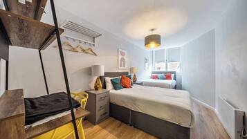 Um quarto moderno com cama, mesas de cabeceira, escrivaninha e luminária suspensa.