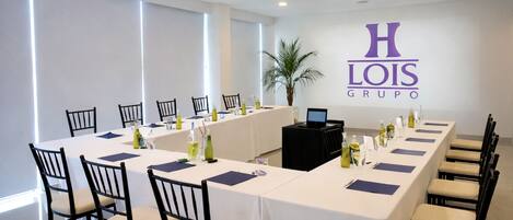 Uma sala de conferências com uma mesa comprida, cadeiras e um logotipo na parede.