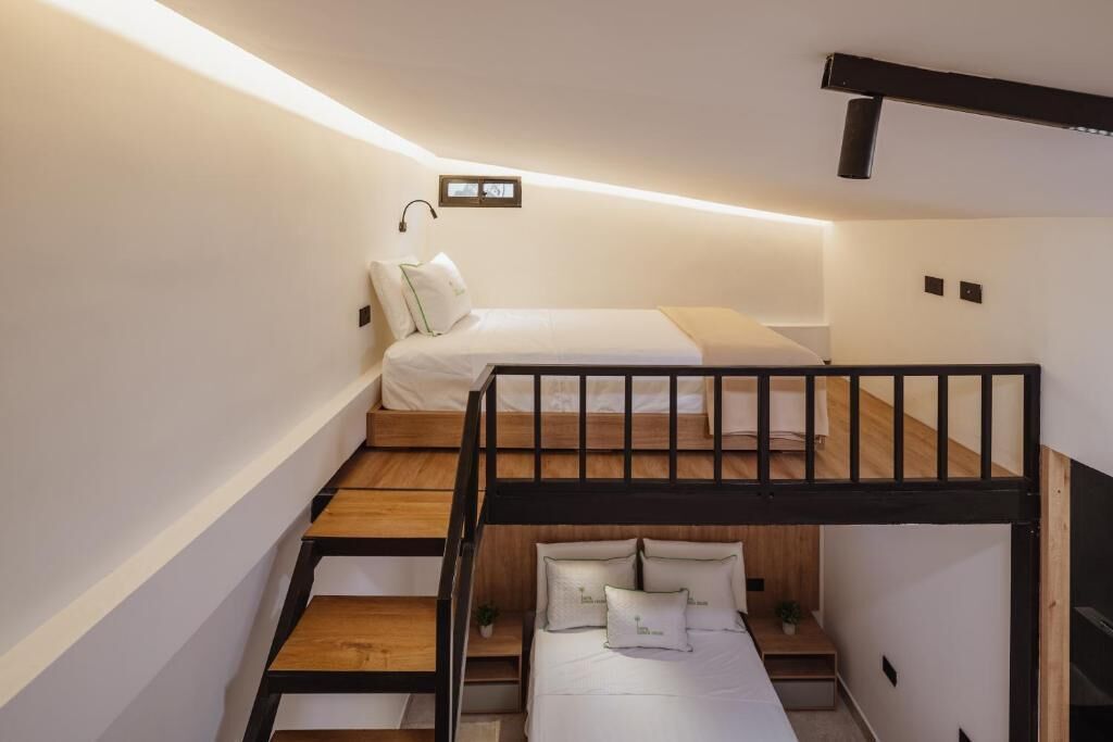 Quarto de hotel pequeno com uma cama beliche, uma escrivaninha e uma mesa de cabeceira.