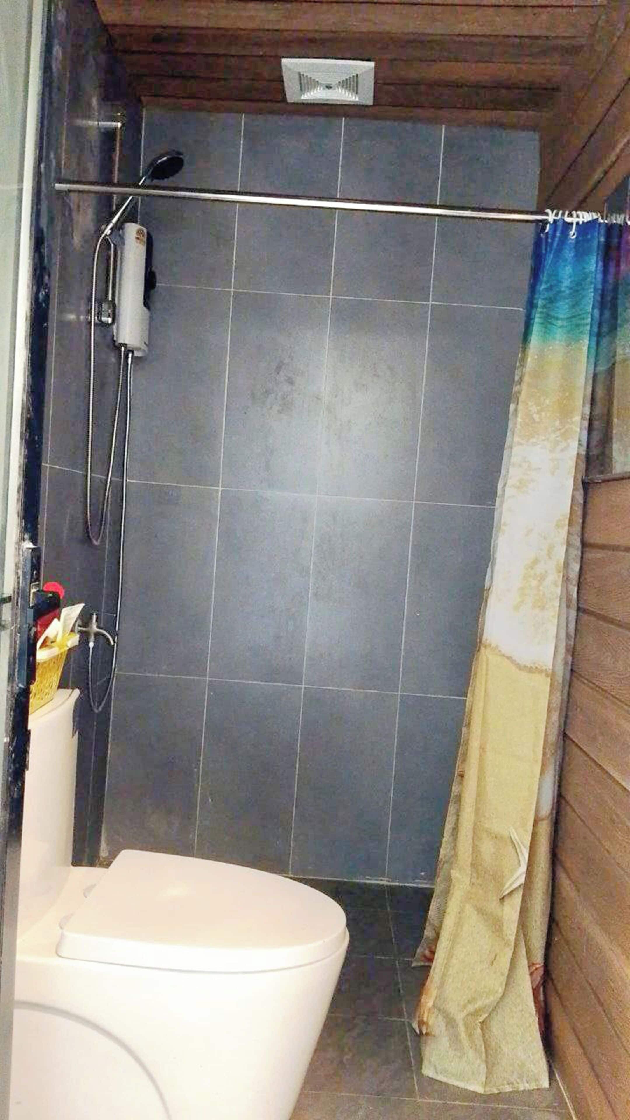 Casa de banho pequena com chuveiro, sanita e porta-toalhas.