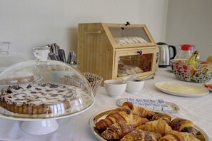 Um buffet de café da manhã com pães, um bolo e uma vitrine de madeira.