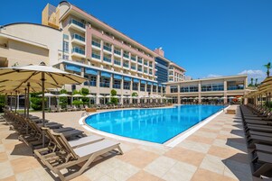 Um hotel com piscina, espreguiçadeiras e guarda-sóis.