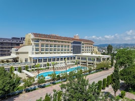 Um hotel com piscina, várias varandas e vista para a paisagem urbana ao redor.