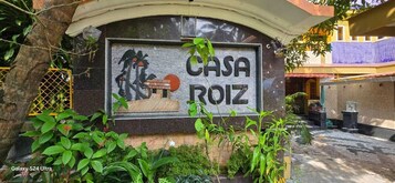 Placa com o nome 'CASA ROIZ' e um mural de uma pessoa e uma palmeira.