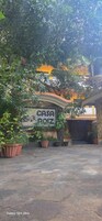 Um pátio com uma placa indicando "CASA ROIZ", rodeado por plantas em vasos e um chão de pedra.