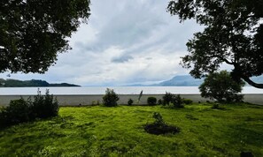 Um campo gramado com um lago e montanhas ao fundo.