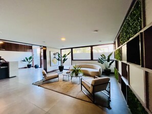 Uma sala de estar ampla com sofá, mesa de centro e plantas em vasos.