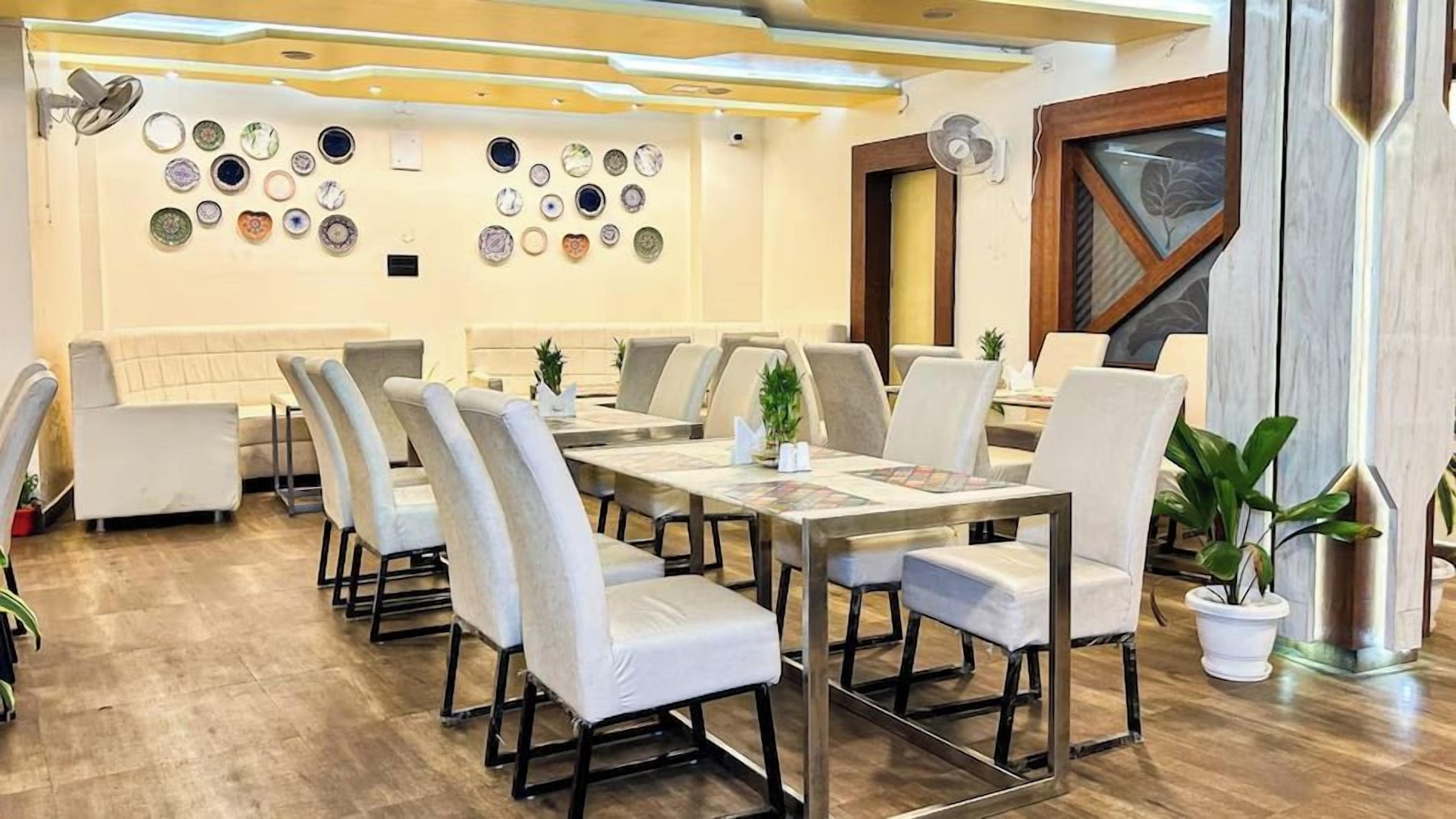 Sala de conferências com cadeiras brancas, uma mesa comprida e uma parede decorada com pratos.