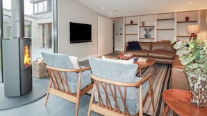Uma sala de estar moderna com lareira, assentos confortáveis, televisão de tela plana e um ambiente acolhedor.