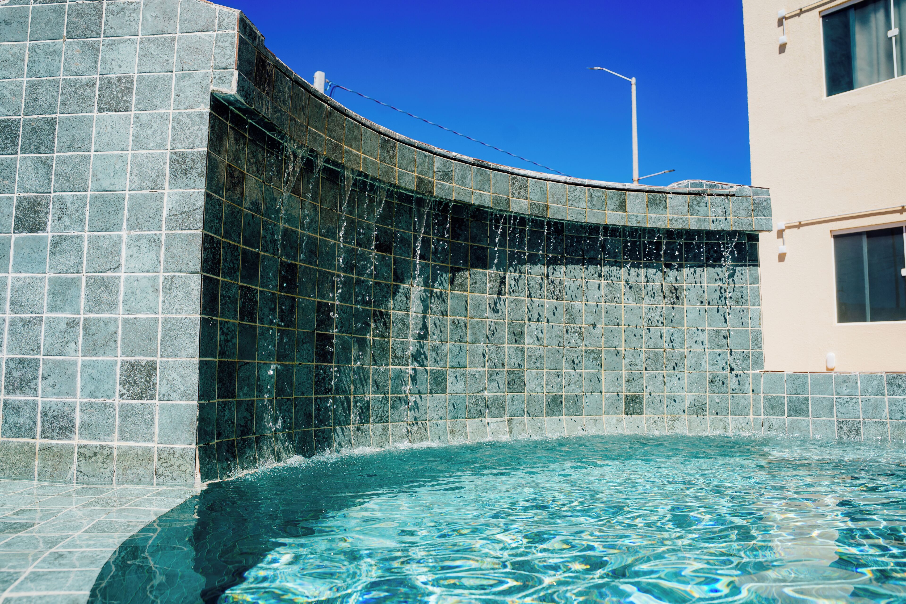 Piscina com parede de azulejos curva e céu azul límpido.