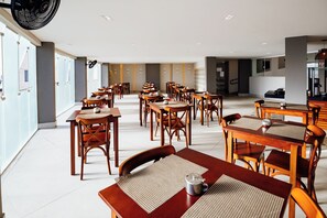 Uma sala de jantar ampla com várias mesas e cadeiras, janelas grandes e design de interiores moderno.