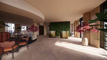 Um hall amplo com teto curvo, área de estar com mesa e cadeiras, parede verde grande e vasos grandes com plantas.