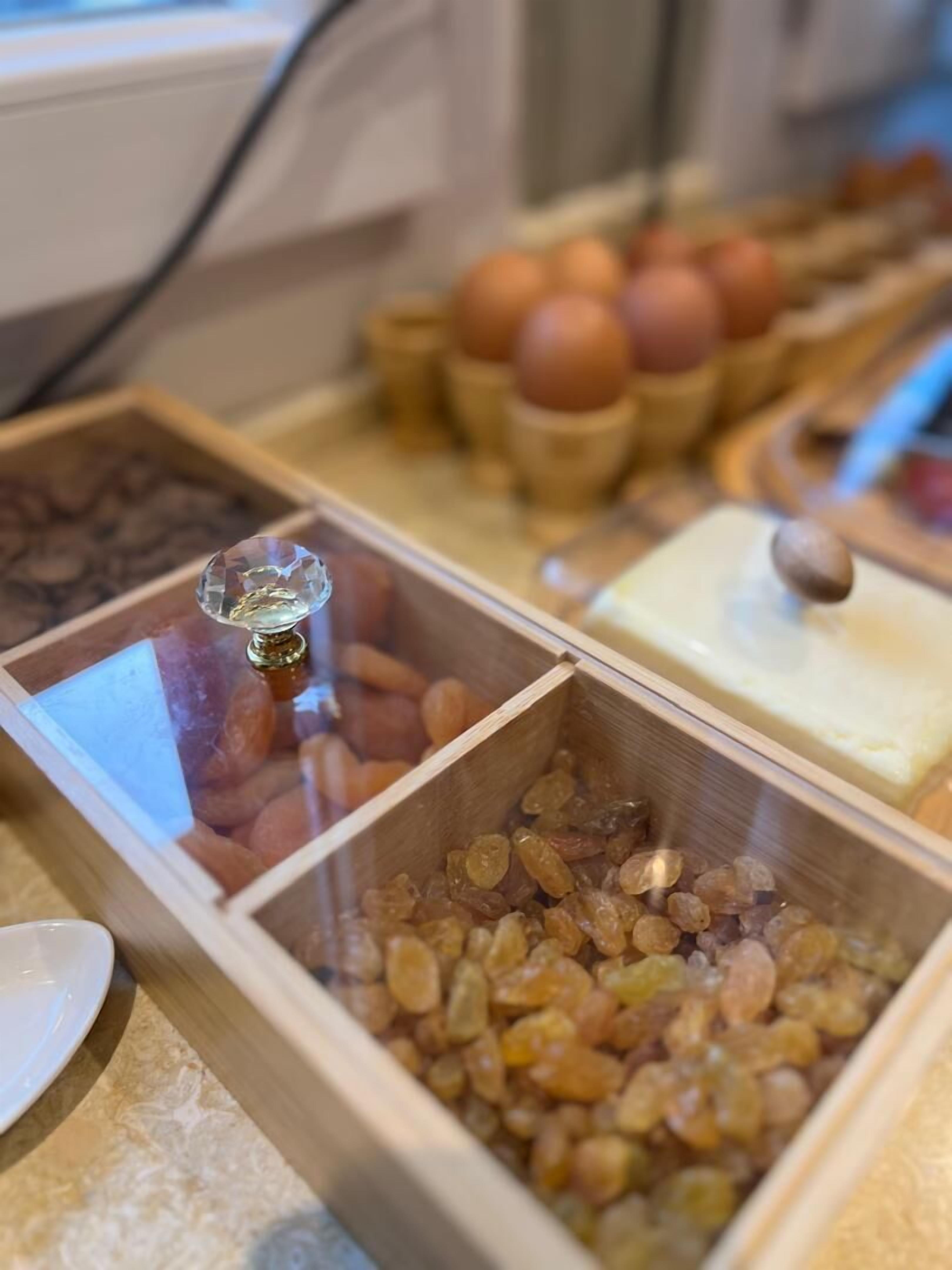 Exposição de diferentes frutos secos e frutas desidratadas em recipientes de madeira.